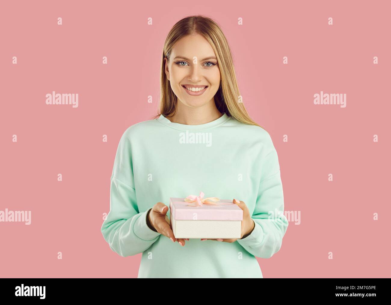 Beautiful satisfied woman holds small festive gift box in her hands on ...