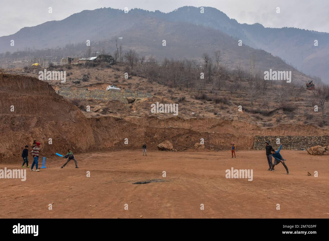 Kashmiri men play cricket on top of the hill during a cold winter day ...