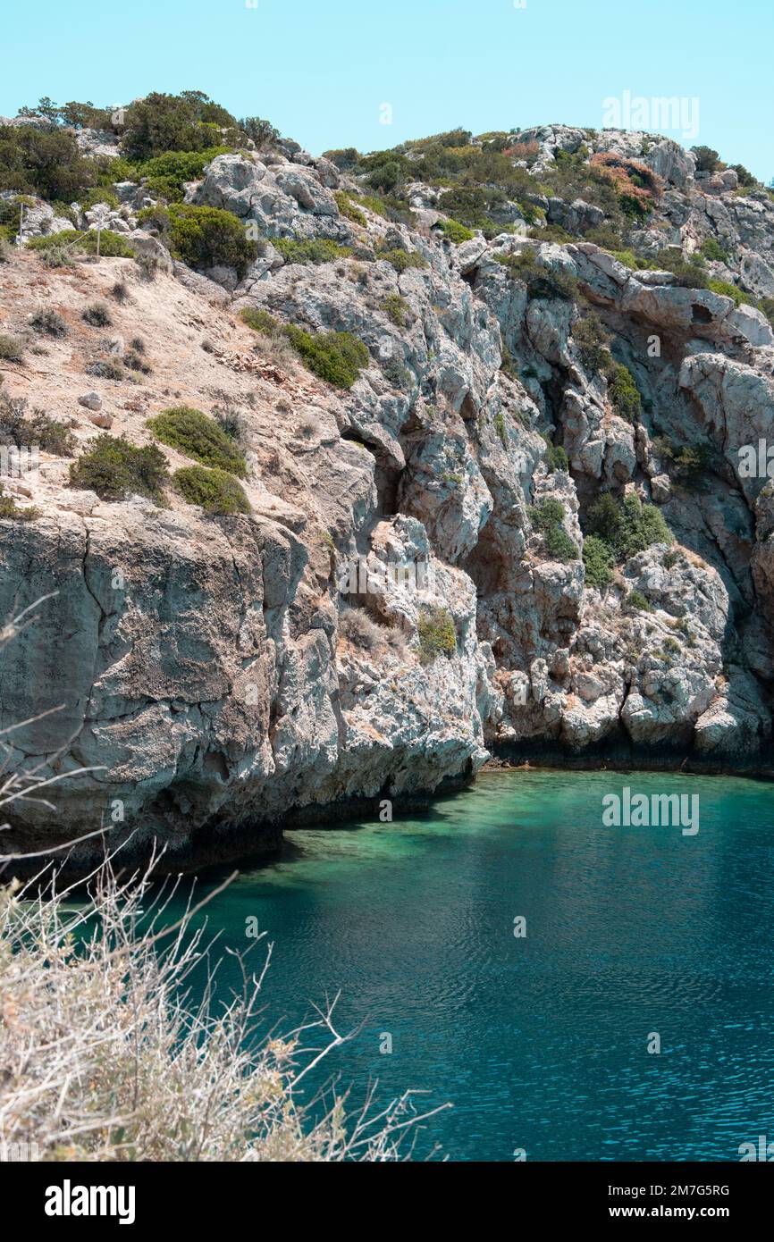 A vertical shot of rough cliffs on a coast of an azure sea Stock Photo ...