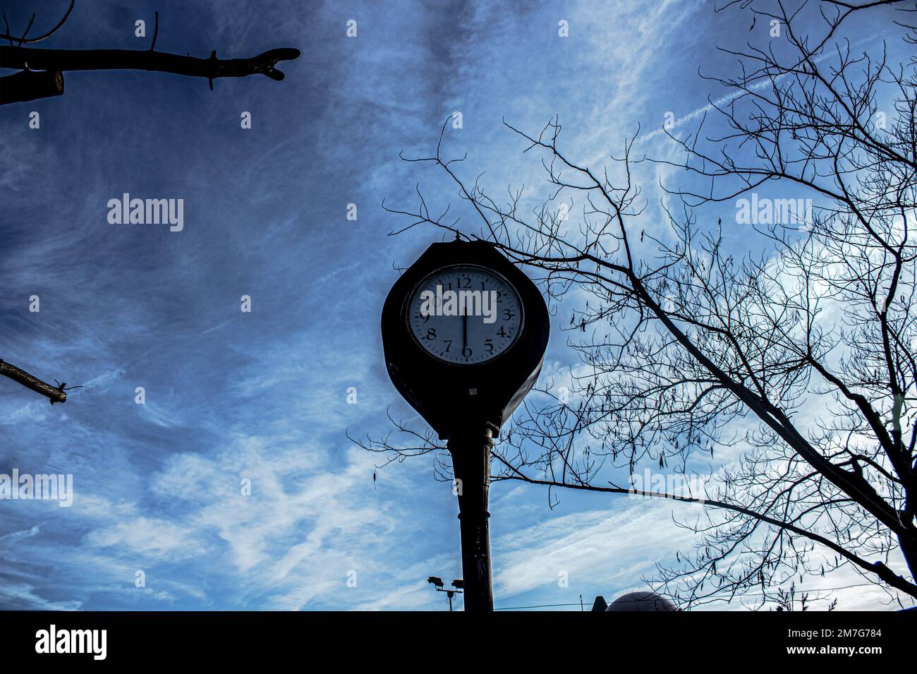 A low-angle shot of a street clock under the blue sky showing half past ...
