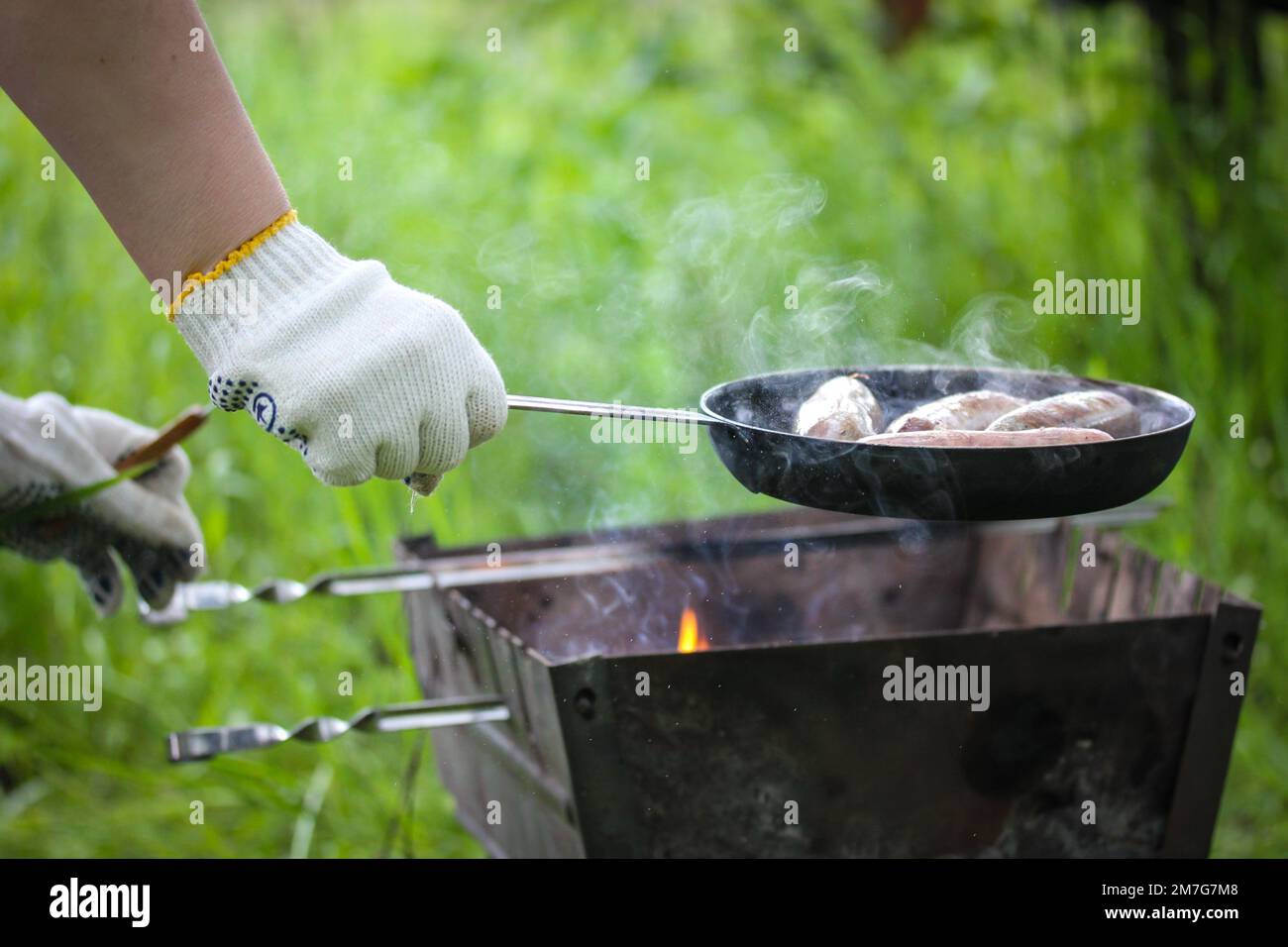 Cooking over campfire in summer park, forest, woods. Meat sausages BBQ ...