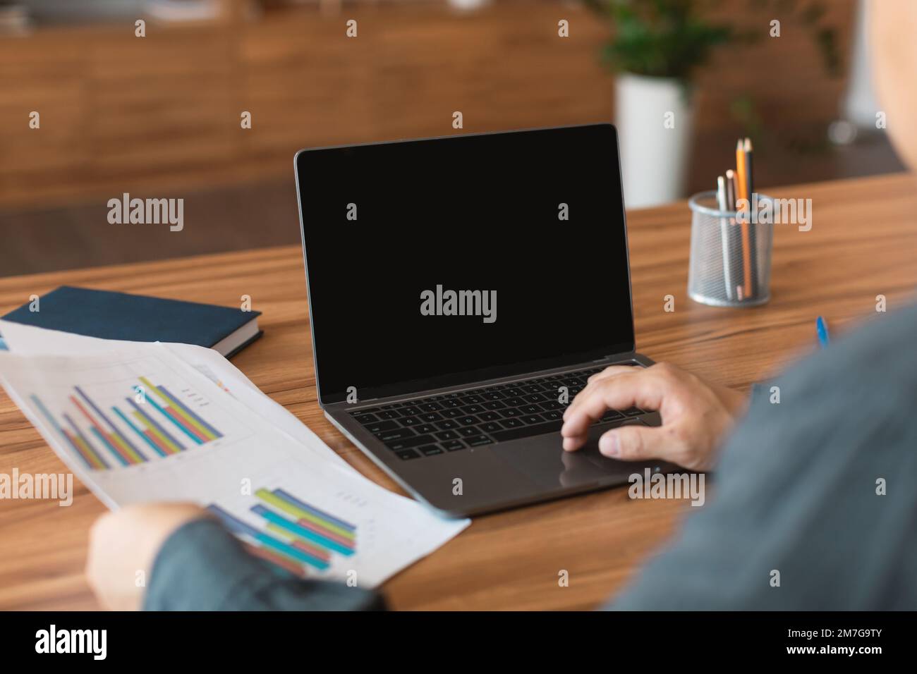 Mature asian male typing on laptop keyboard with empty screen, works ...