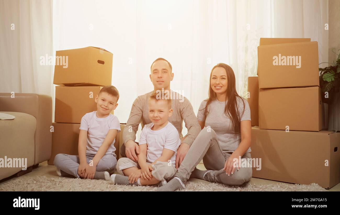 Family with excited expression sits on floor among boxes Stock Photo ...