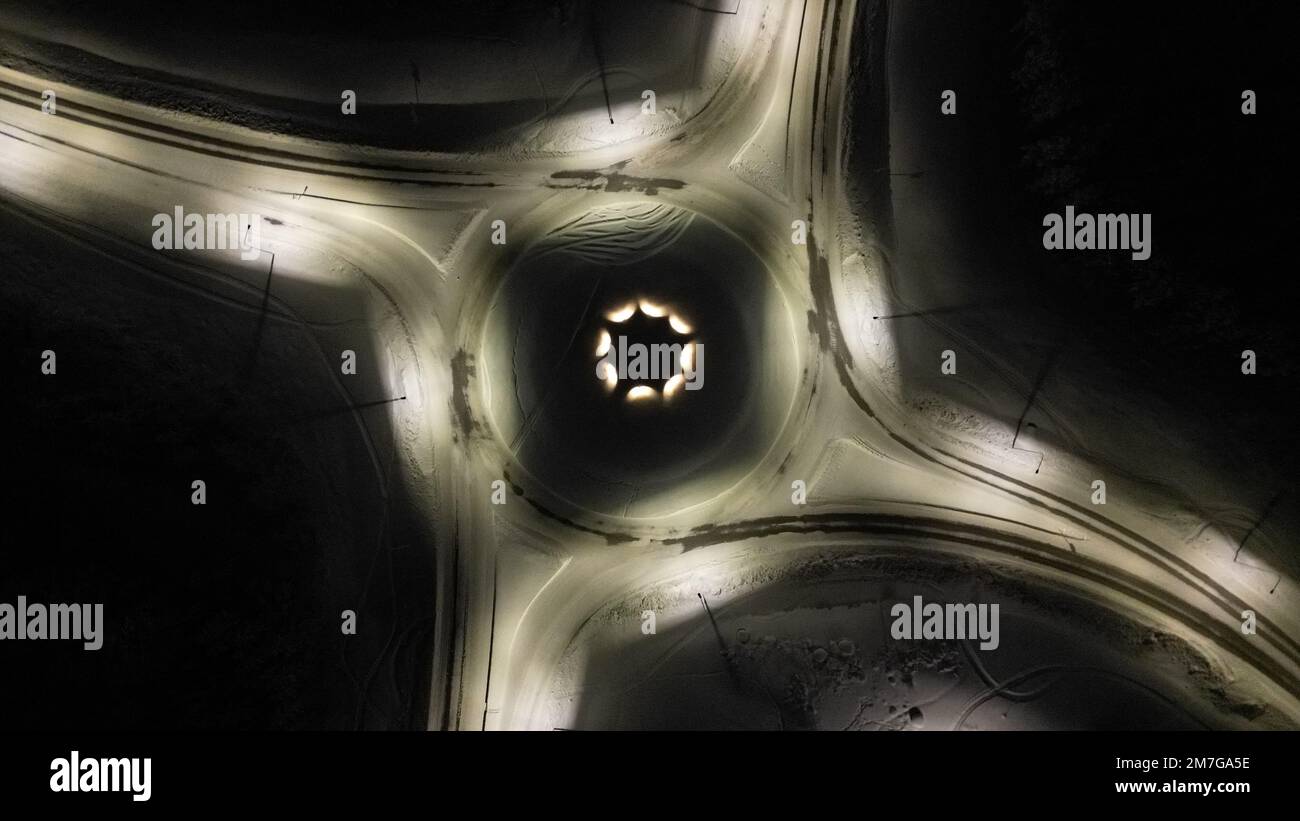 An aerial view of slightly illuminated empty suburban roundabout in ...