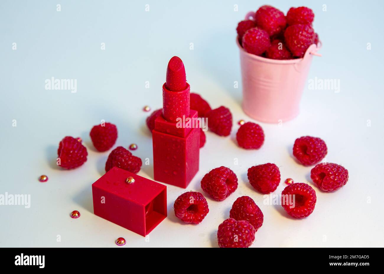 Bright red lipstick and ripe juicy raspberries on white background ...