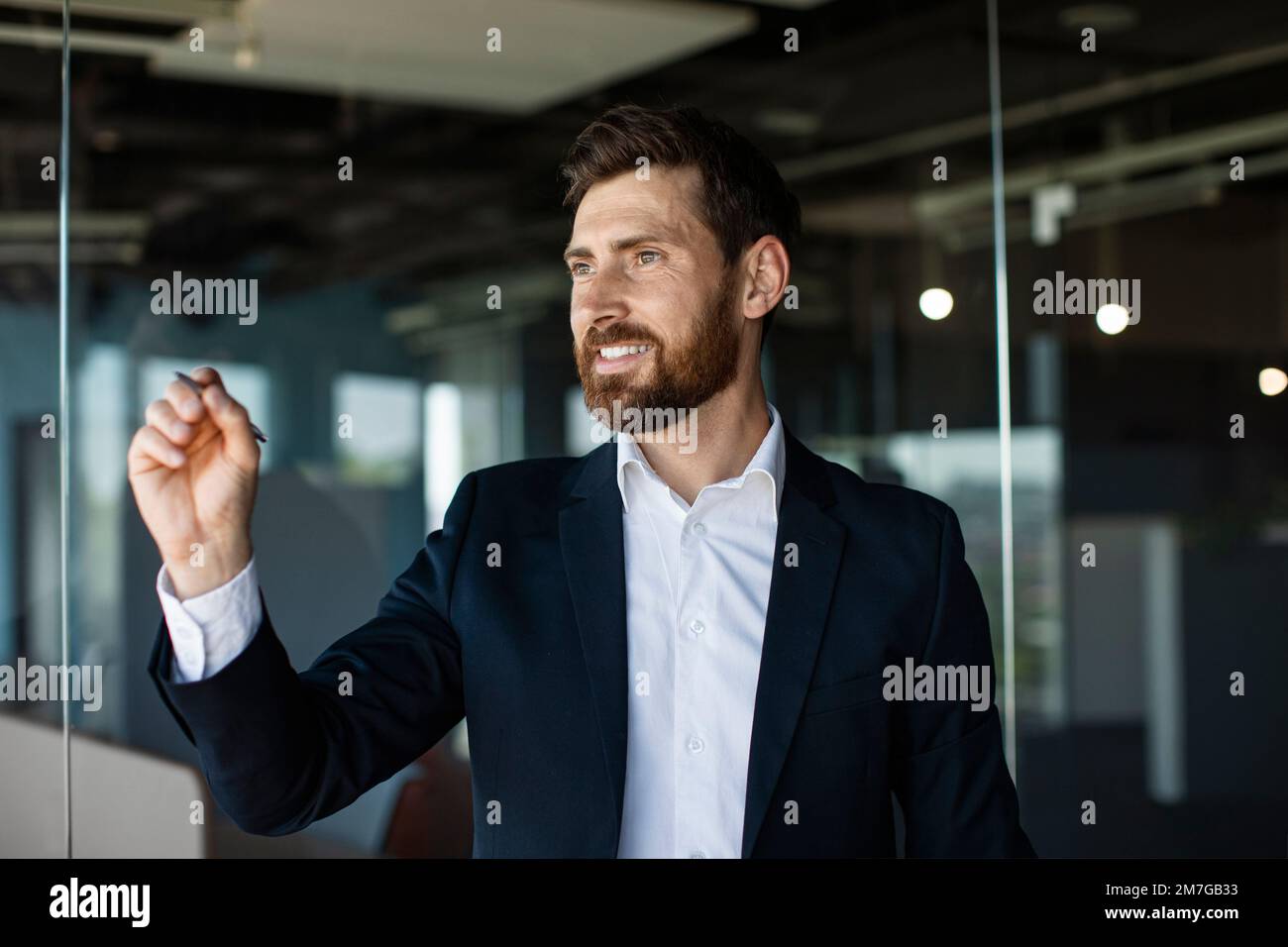 Confident middle aged businessman writing something on virtual screen ...
