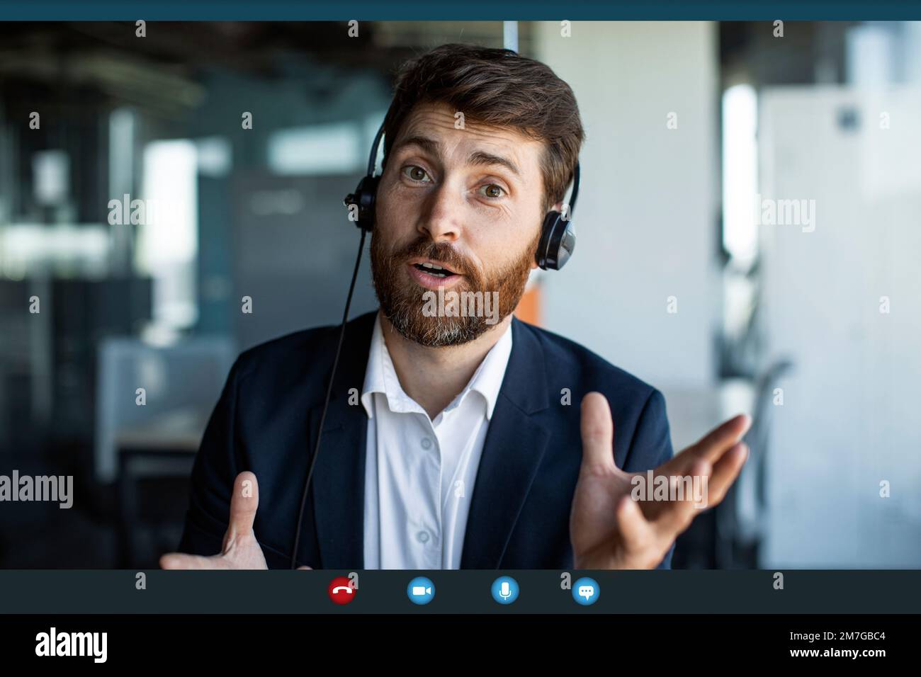 Businessman making video call from office, wearing headphones and ...