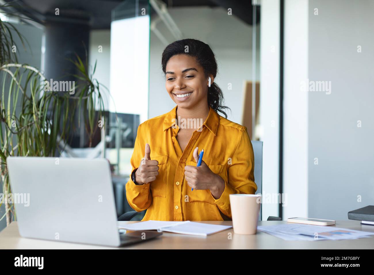 E-teaching. Happy black female business tutor gesturing thumbs up to ...