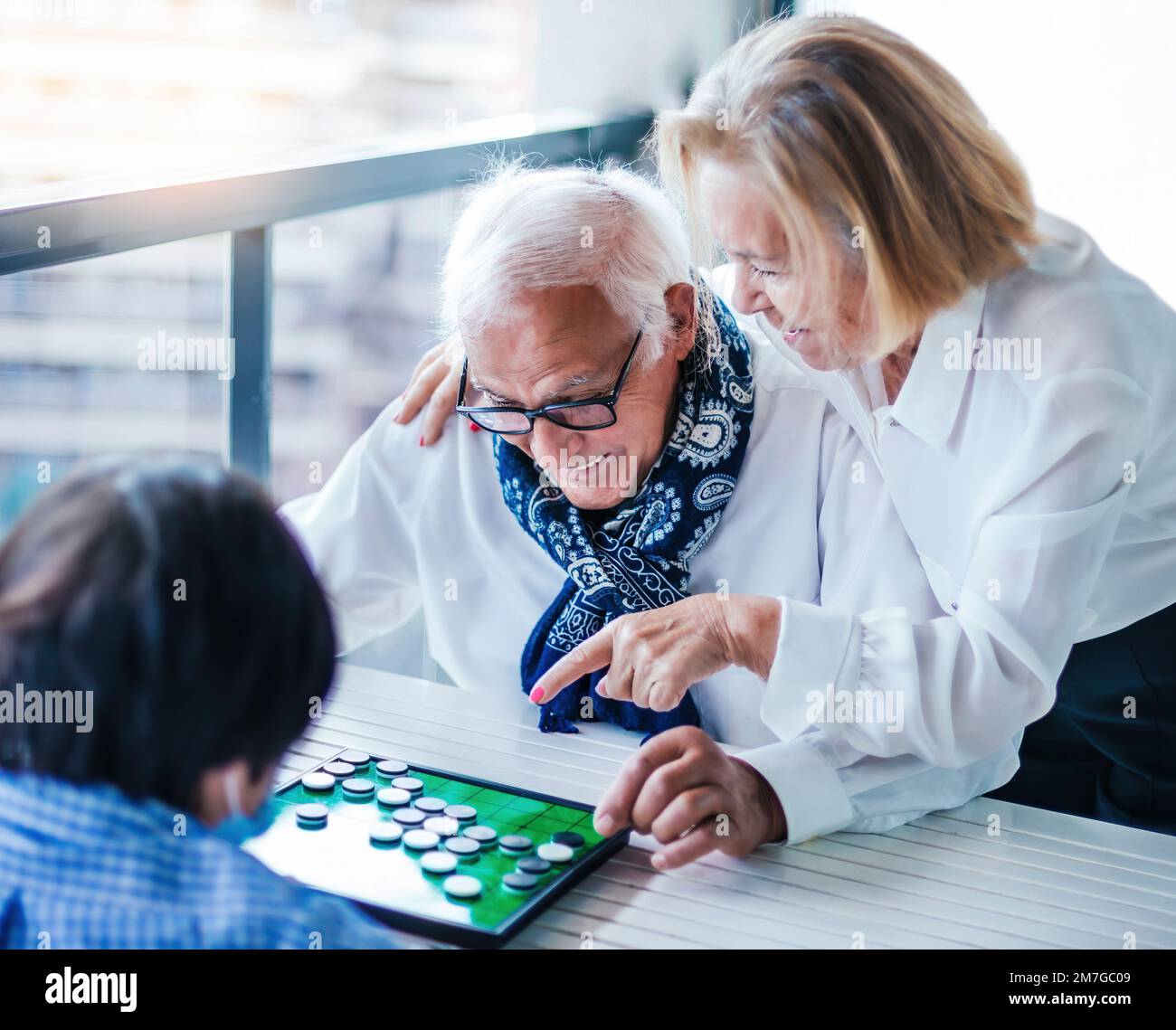 selective blur. grandparents having fun while playing a board game with ...