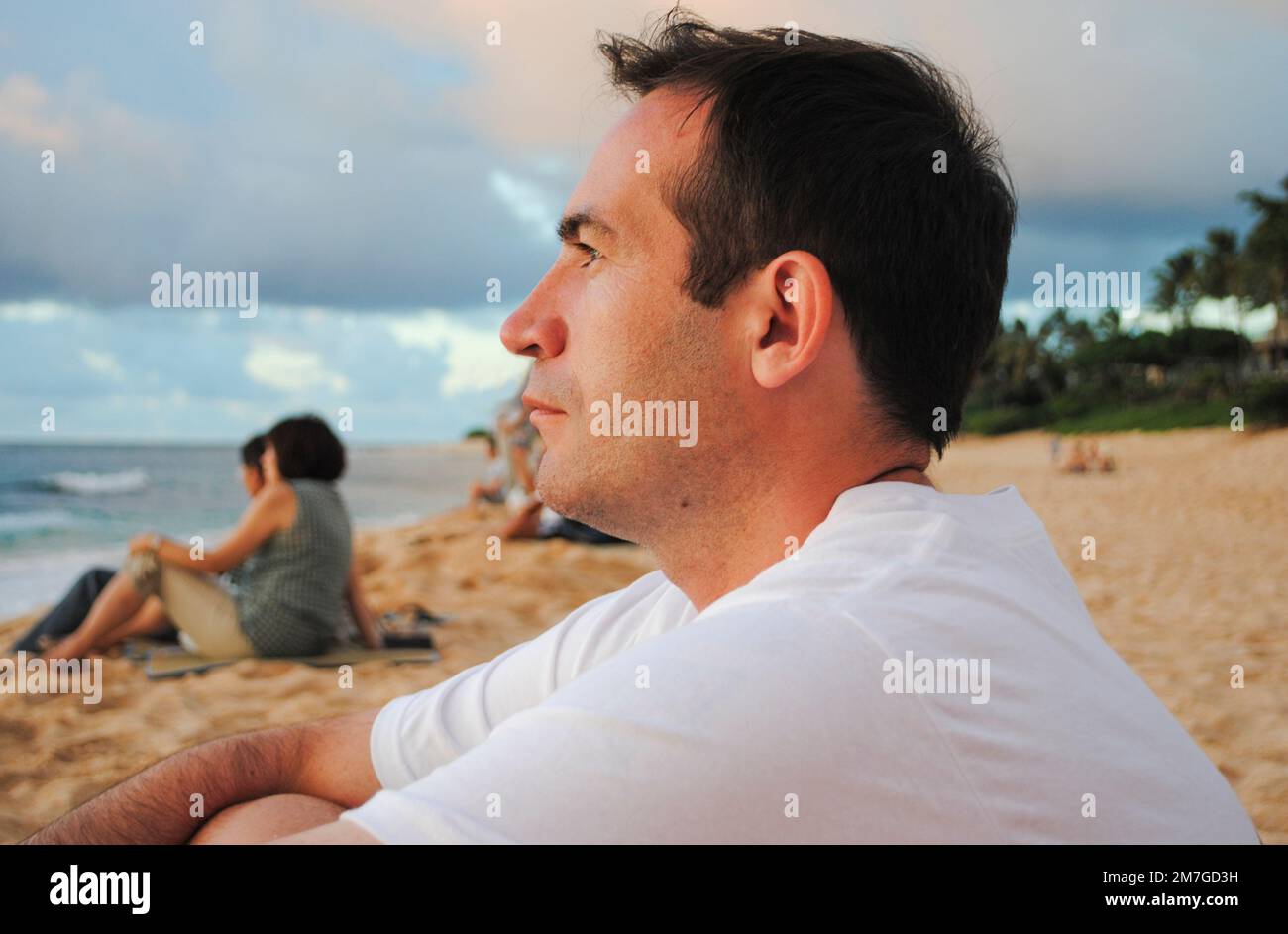 Side view of a young handsome man watching the sunset in Sunset Beach ...