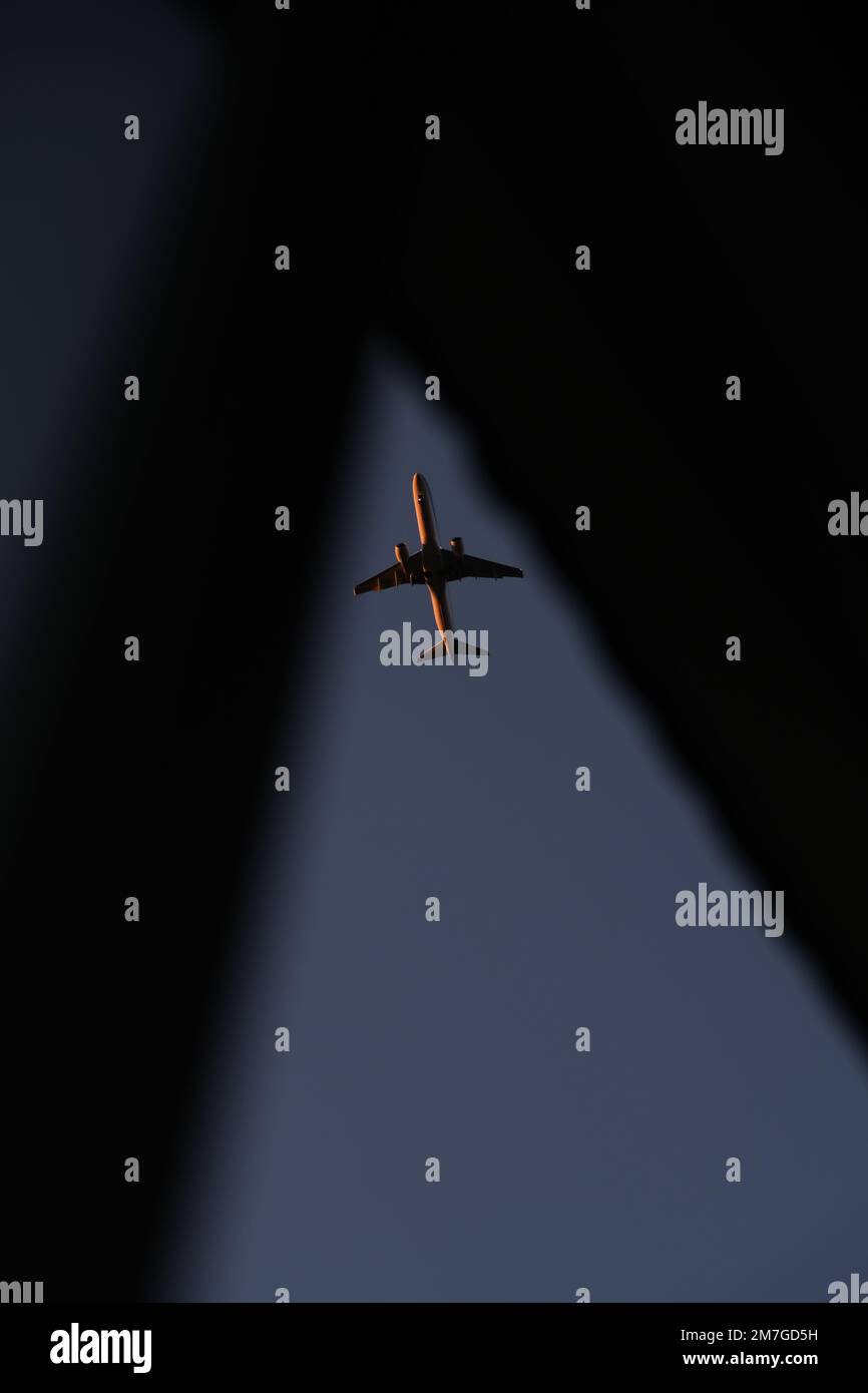 A vertical shot of a commercial plane seen flying in the air through a ...