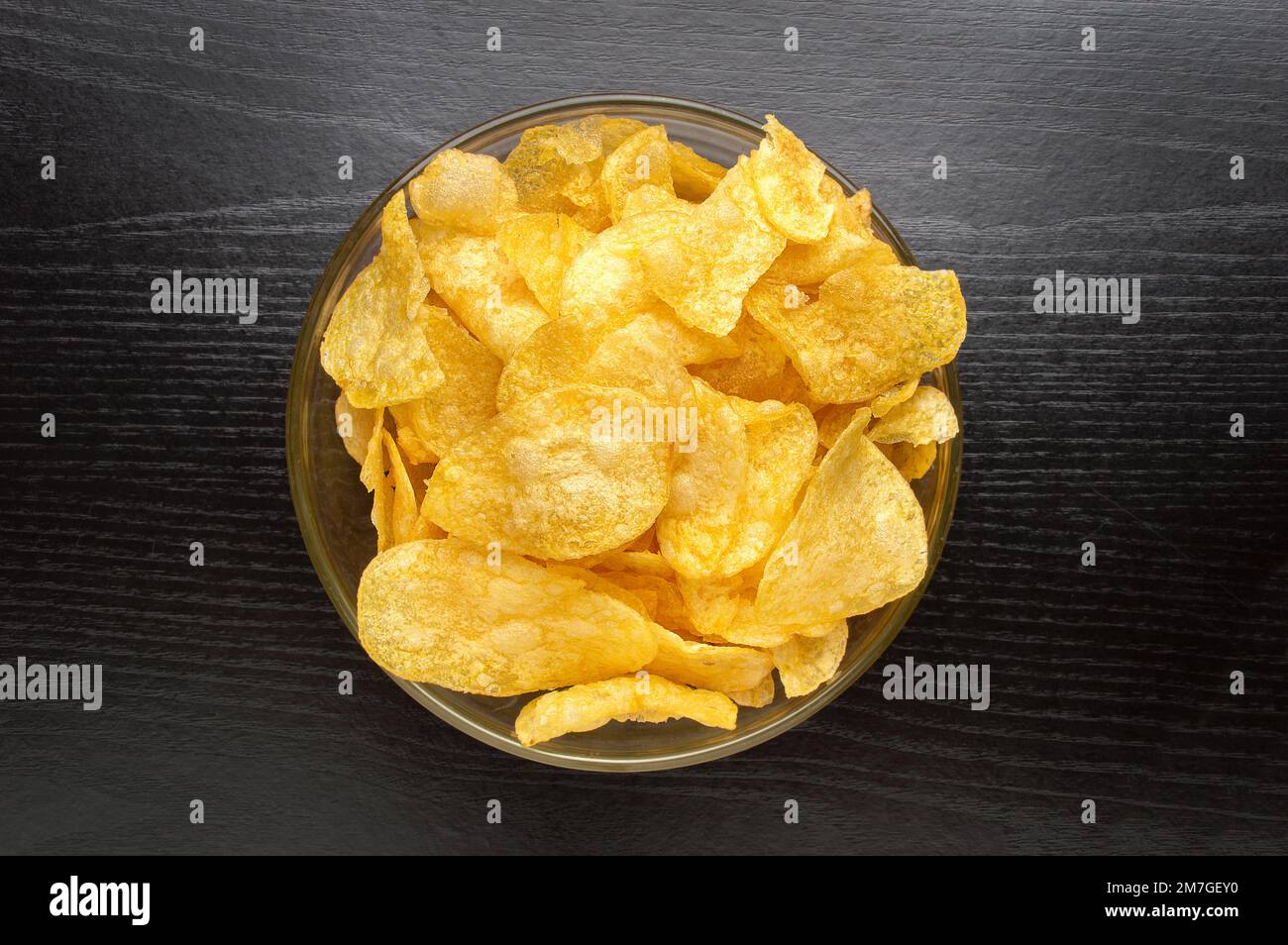 Top view shot of a bowl of potato chips on black background. Concept of ...