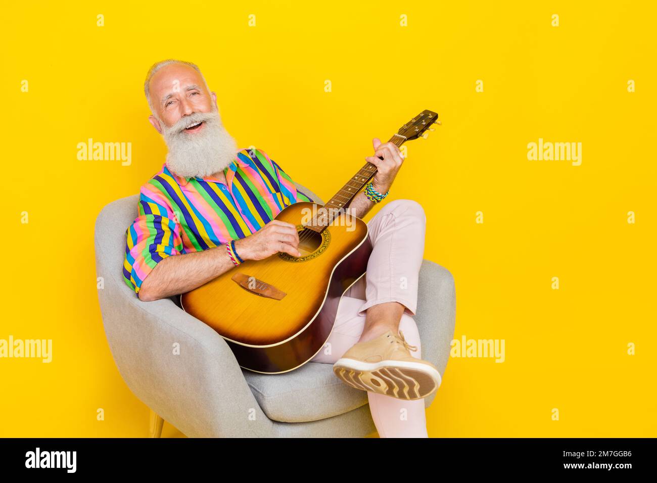 Full size photo of cheerful handsome person sit armchair play guitar ...