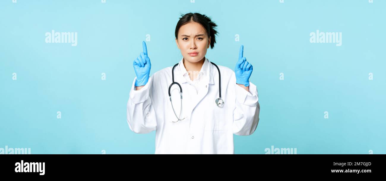 Angry and concerned female doctor, physician pointing fingers up ...