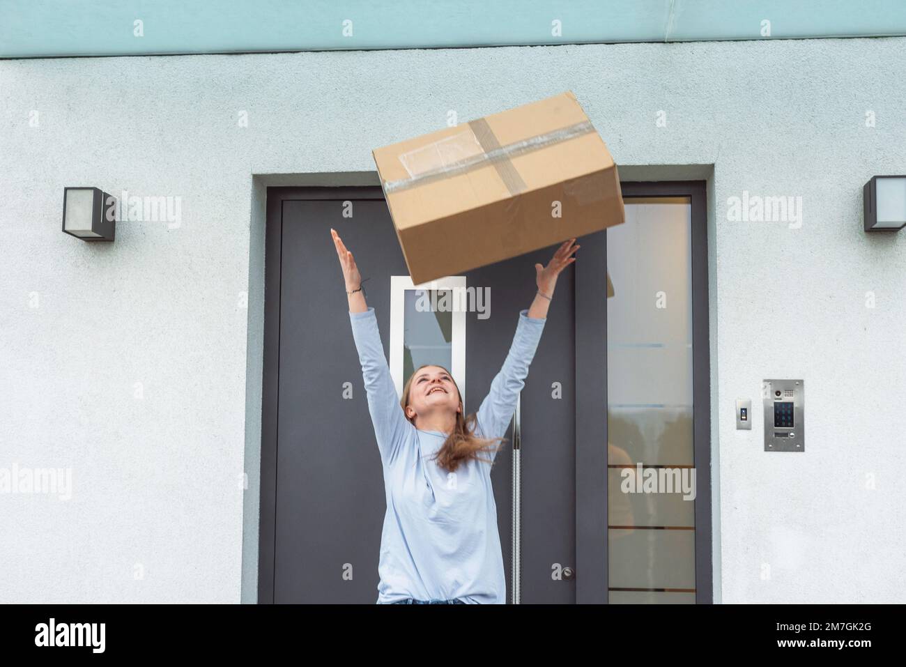 Waist up caucasian woman throwing an exciting package in the air ...