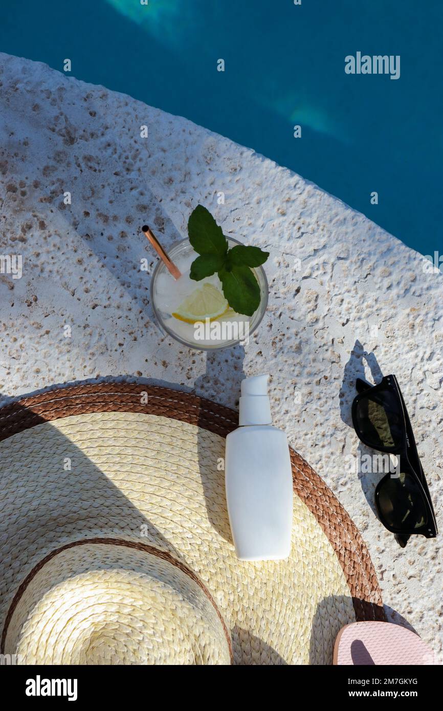 Refreshing glass of water with lemon, straw hat, sunglasses and ...