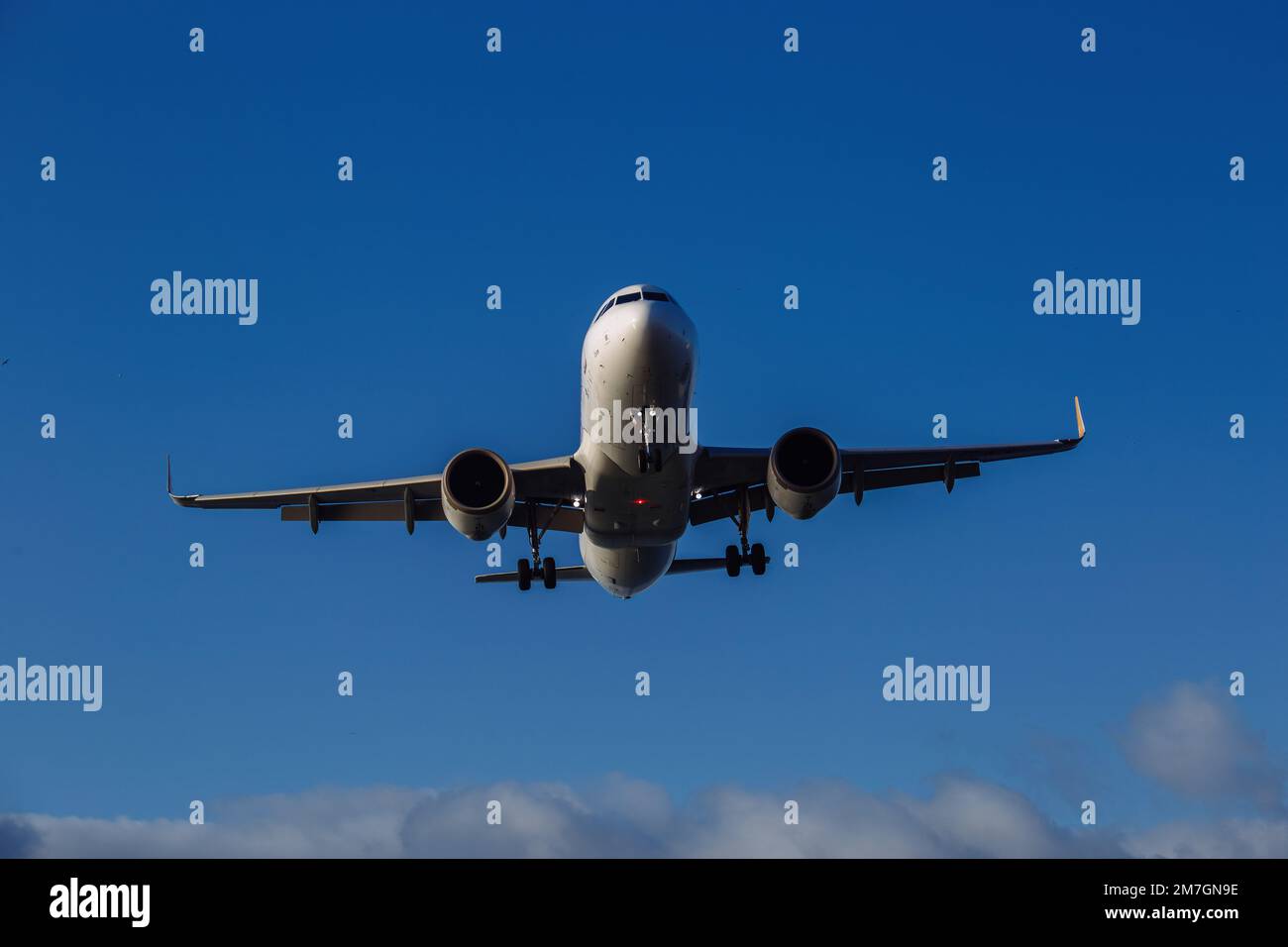Landing plane on cloudy sky background, front view Stock Photo - Alamy