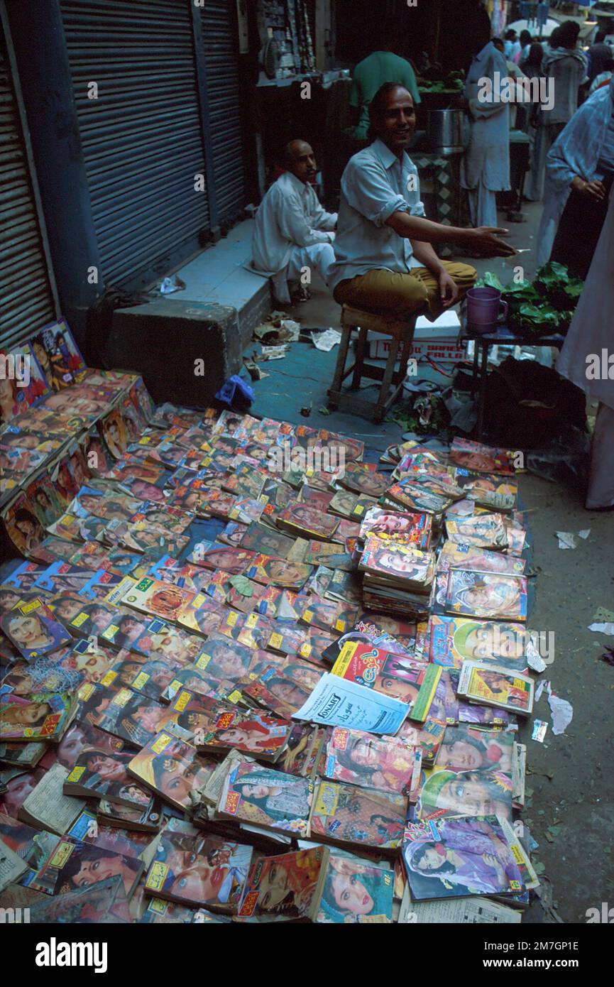 Outdoor women's magazine-seller with magazines on pavement, Old Delhi ...