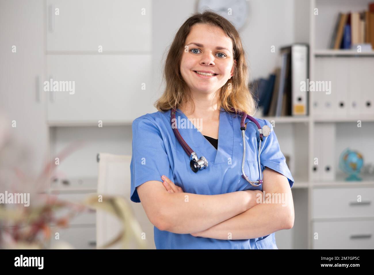 Portrait of female doctor who is working and posing on her workplace in ...