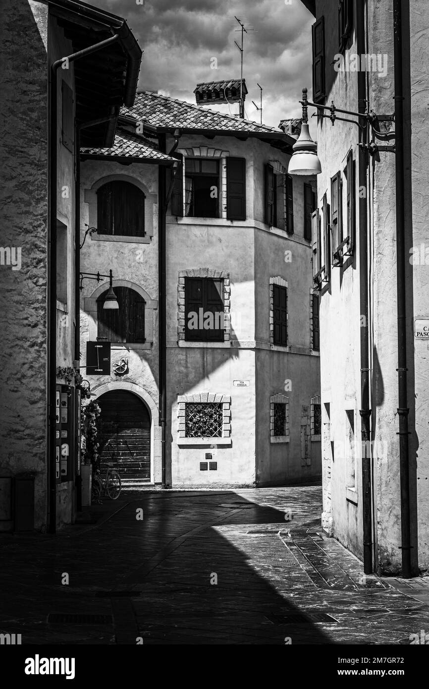 A grayscale vertical shot of small street with old buildings Stock ...
