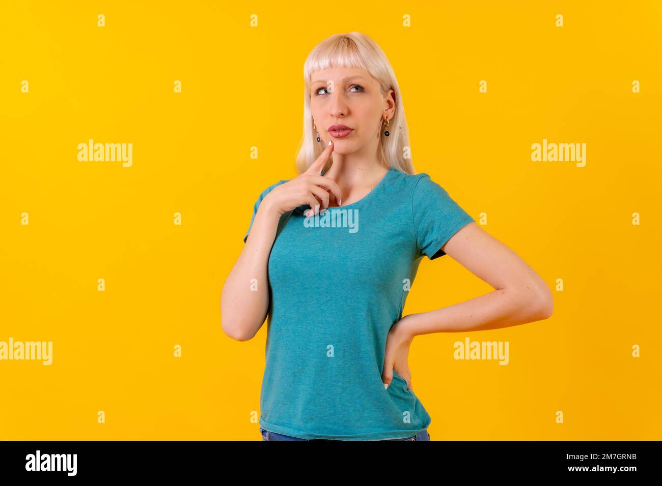 Portrait with pensive pose, blonde caucasian girl in studio on yellow ...