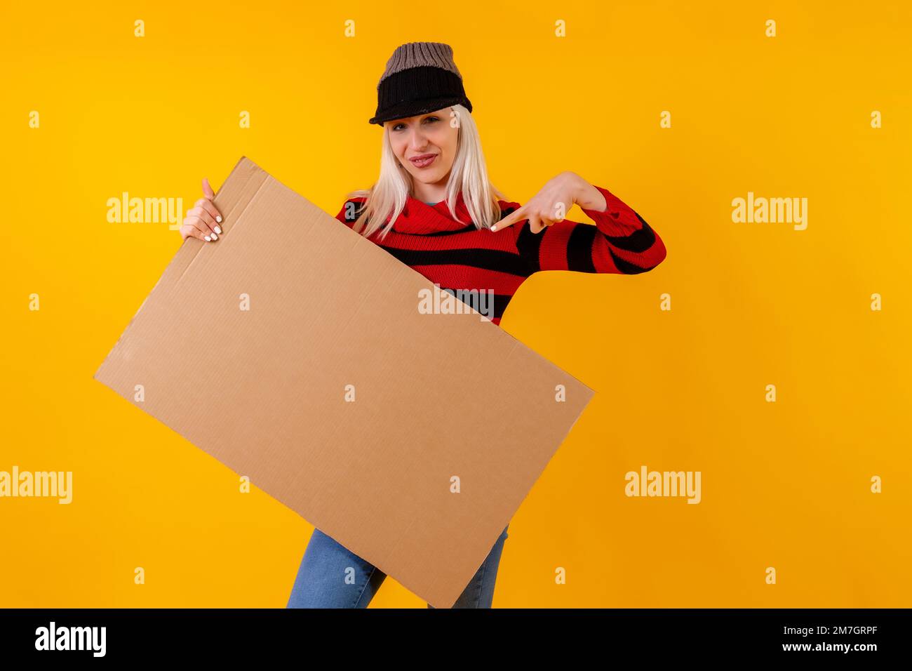 Pointing to empty cardboard advertisement poster, blonde caucasian girl ...