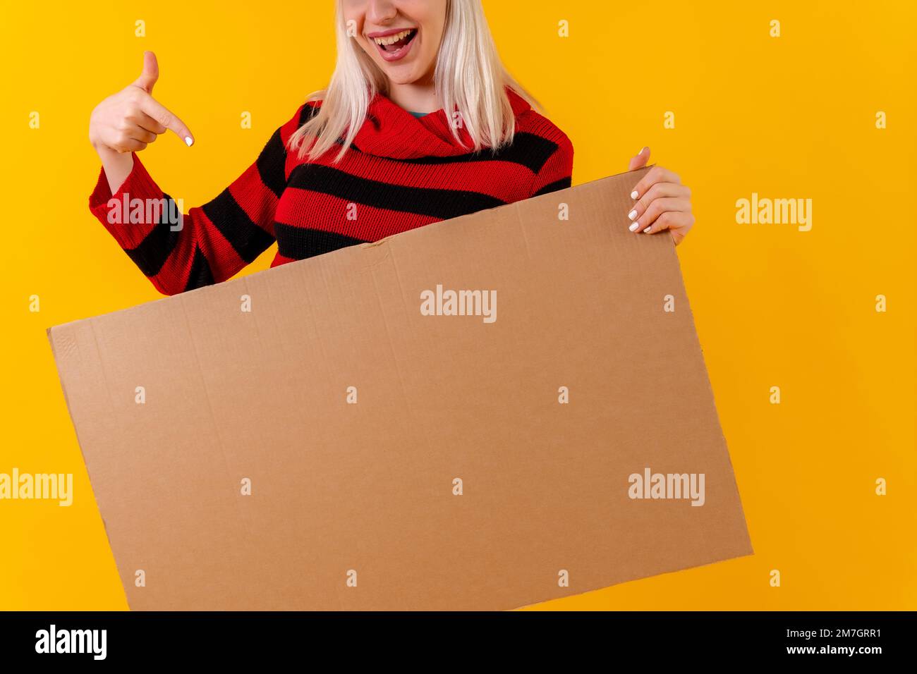Pointing to empty cardboard advertisement poster, blonde caucasian girl ...