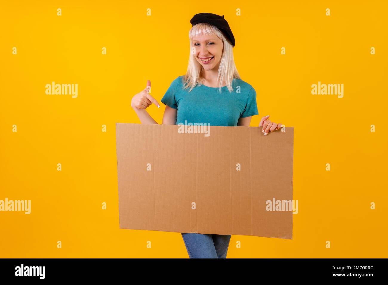 Smiling and pointing at empty cardboard advertisement poster, blonde ...
