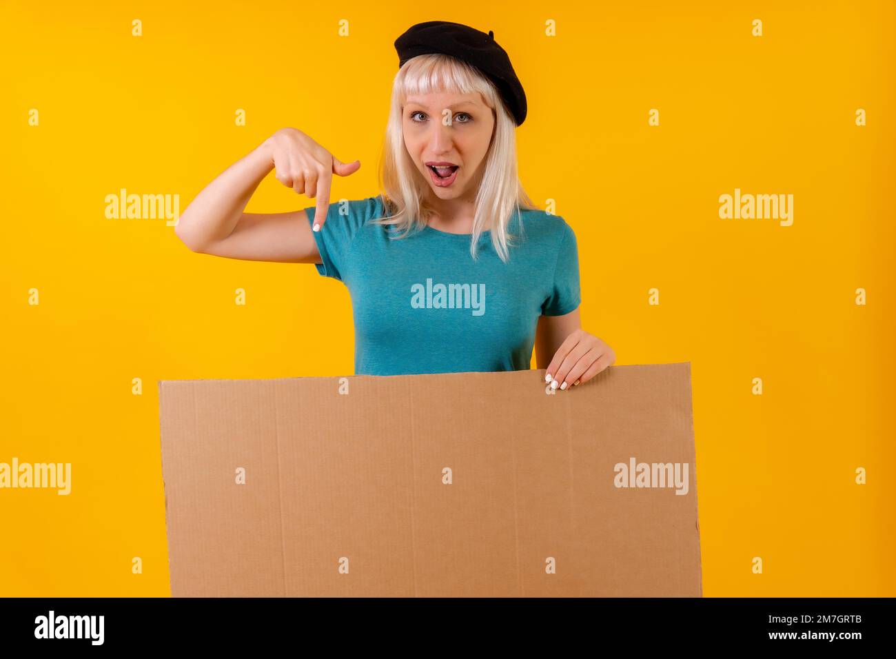 Pointing down a cardboard advertisement poster, blonde caucasian girl ...
