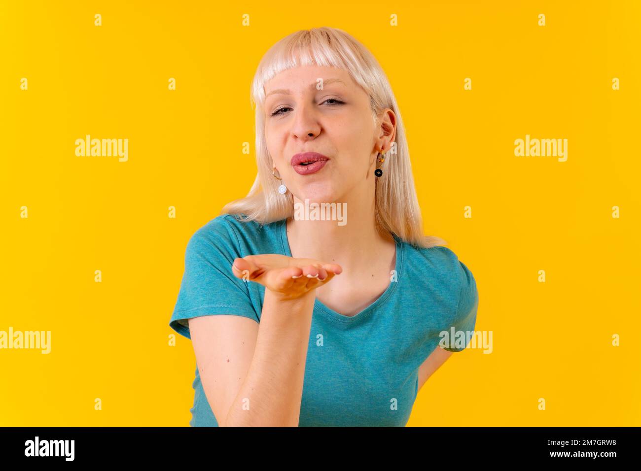 Smiling blowing a kiss to camera, blonde caucasian girl in studio on ...
