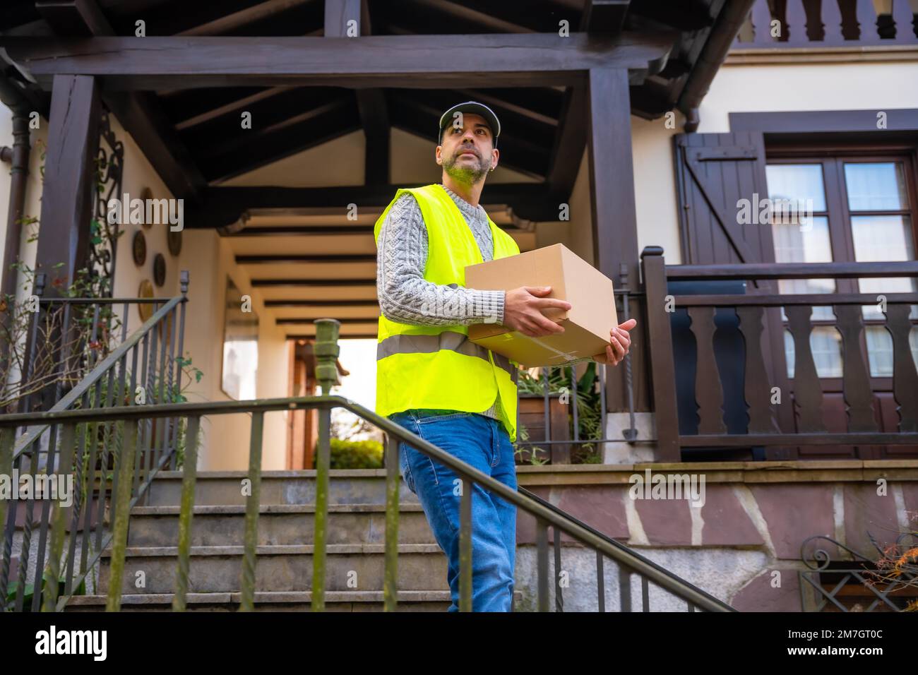 A young delivery man with a box and in a protective uniform at the ...