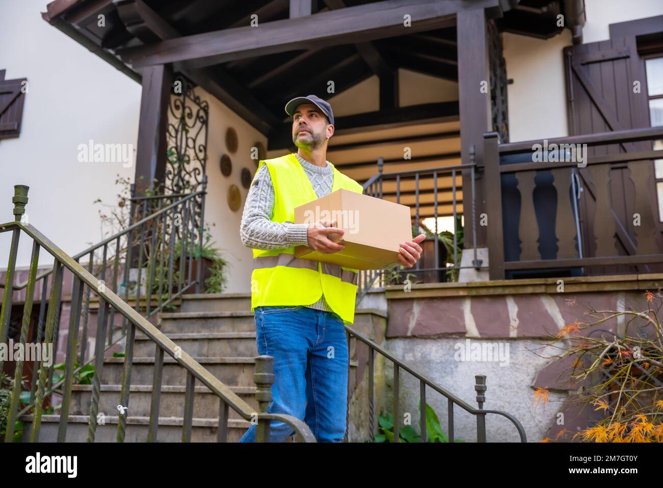 A young delivery man with a box and in a protective uniform at the ...