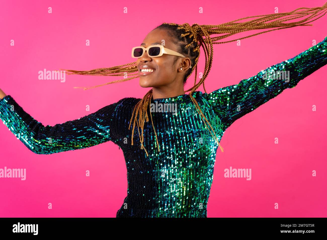African young woman with party braids on a pink background, having fun ...