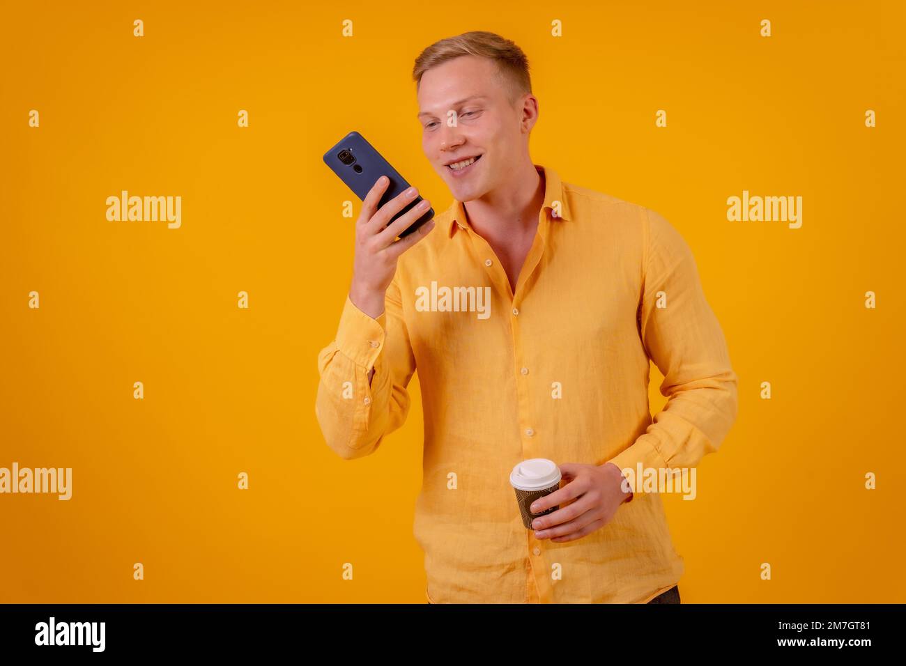 Blond caucasian man on a yellow background, smiling calling friends ...