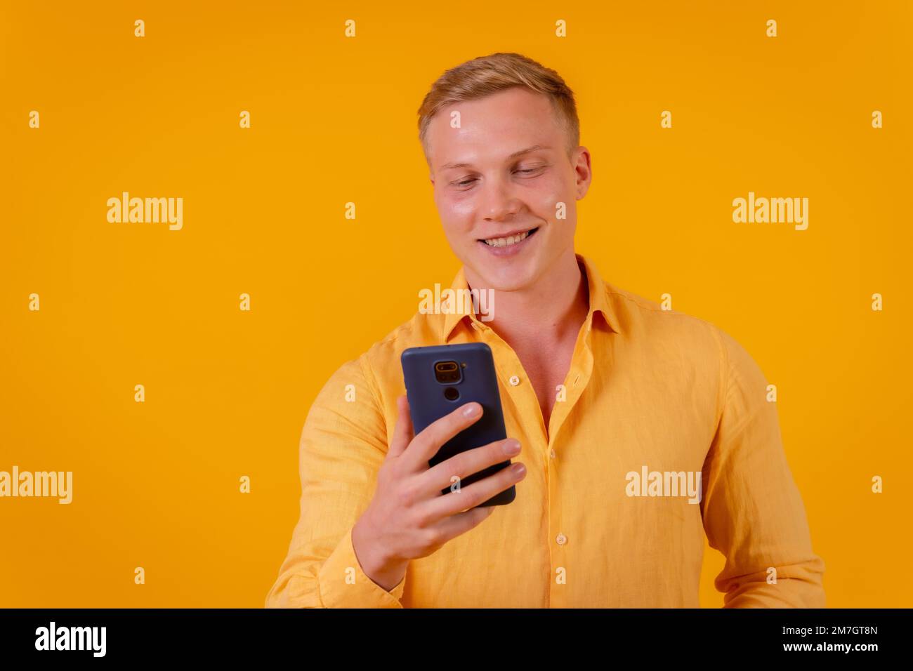 Blond caucasian man on a yellow background, smiling calling friends ...