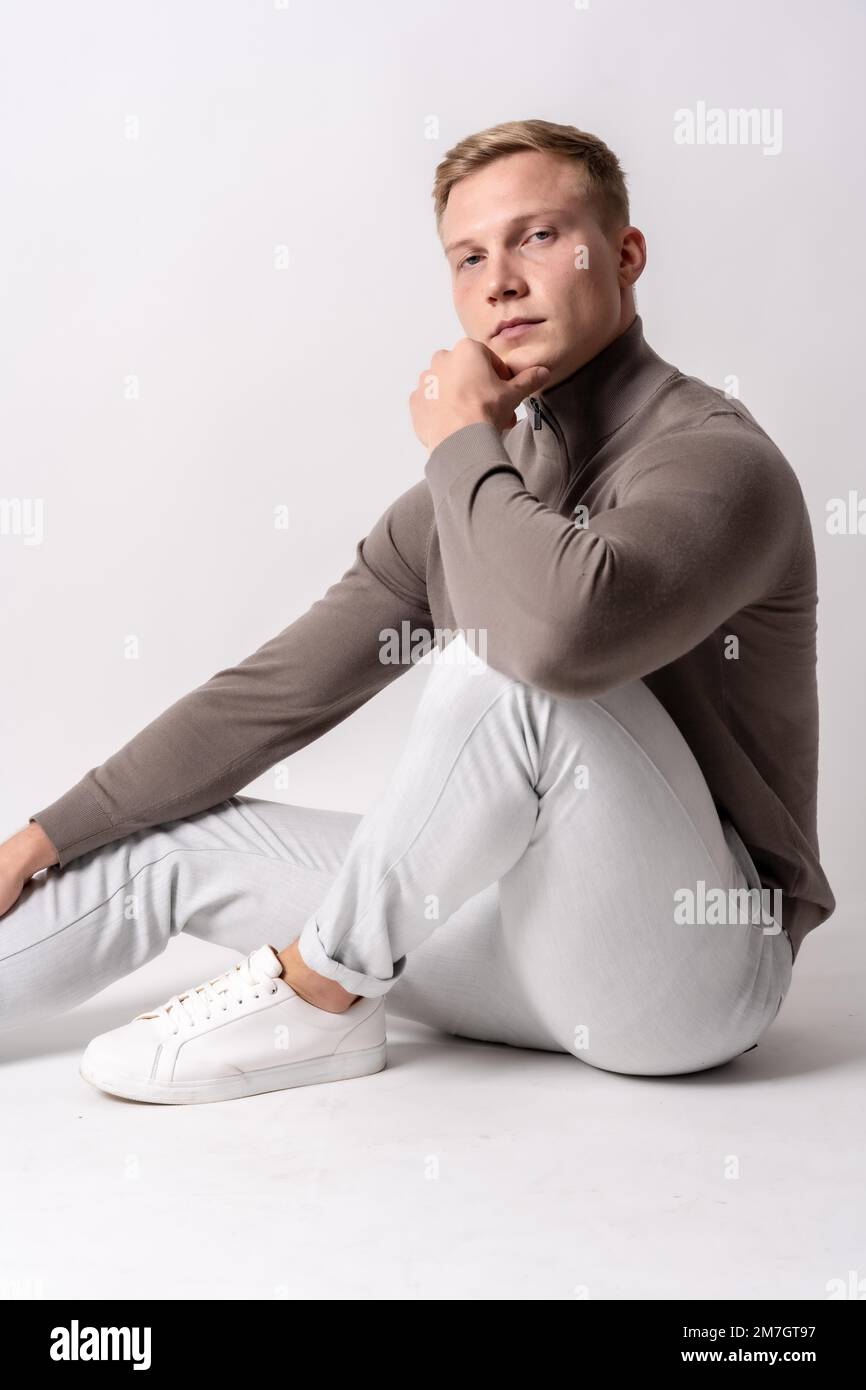 Caucasian blond model with a brown sweater on a white background ...