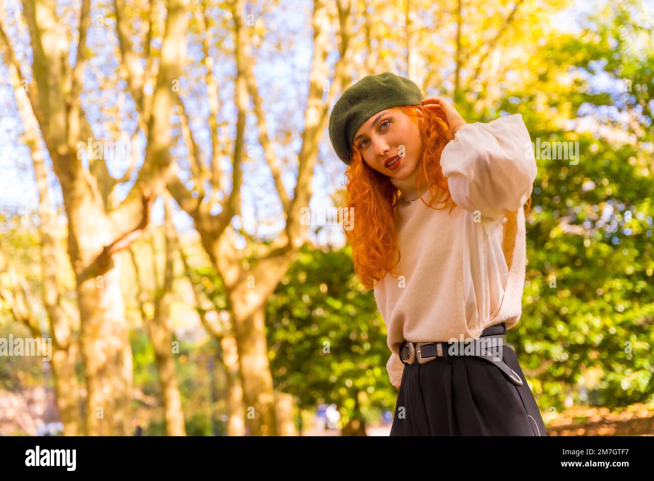 Portrait of red-haired woman with beret in a park, forest at sunset ...