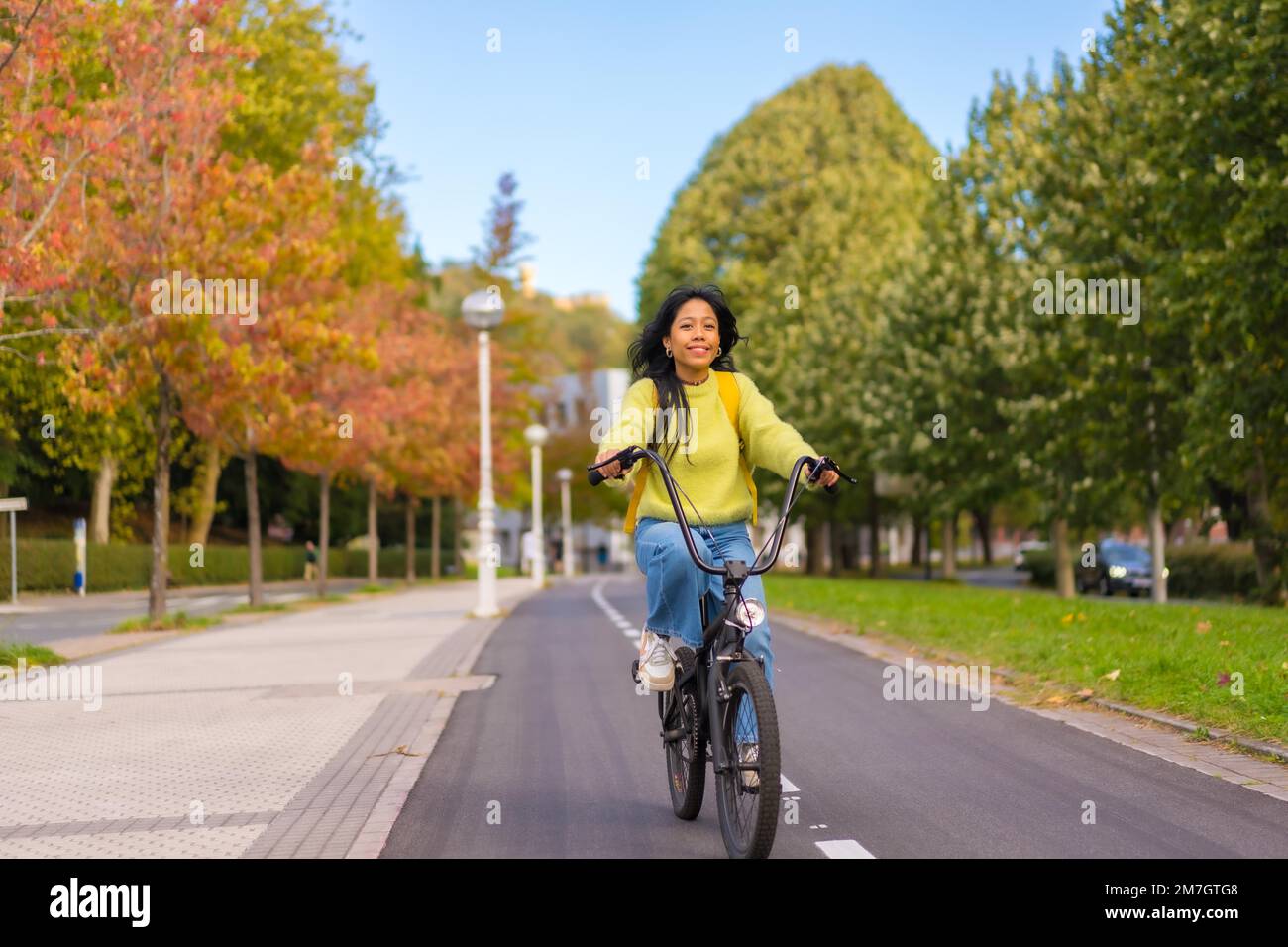 Young Asian female student riding a bicycle on her way to university ...