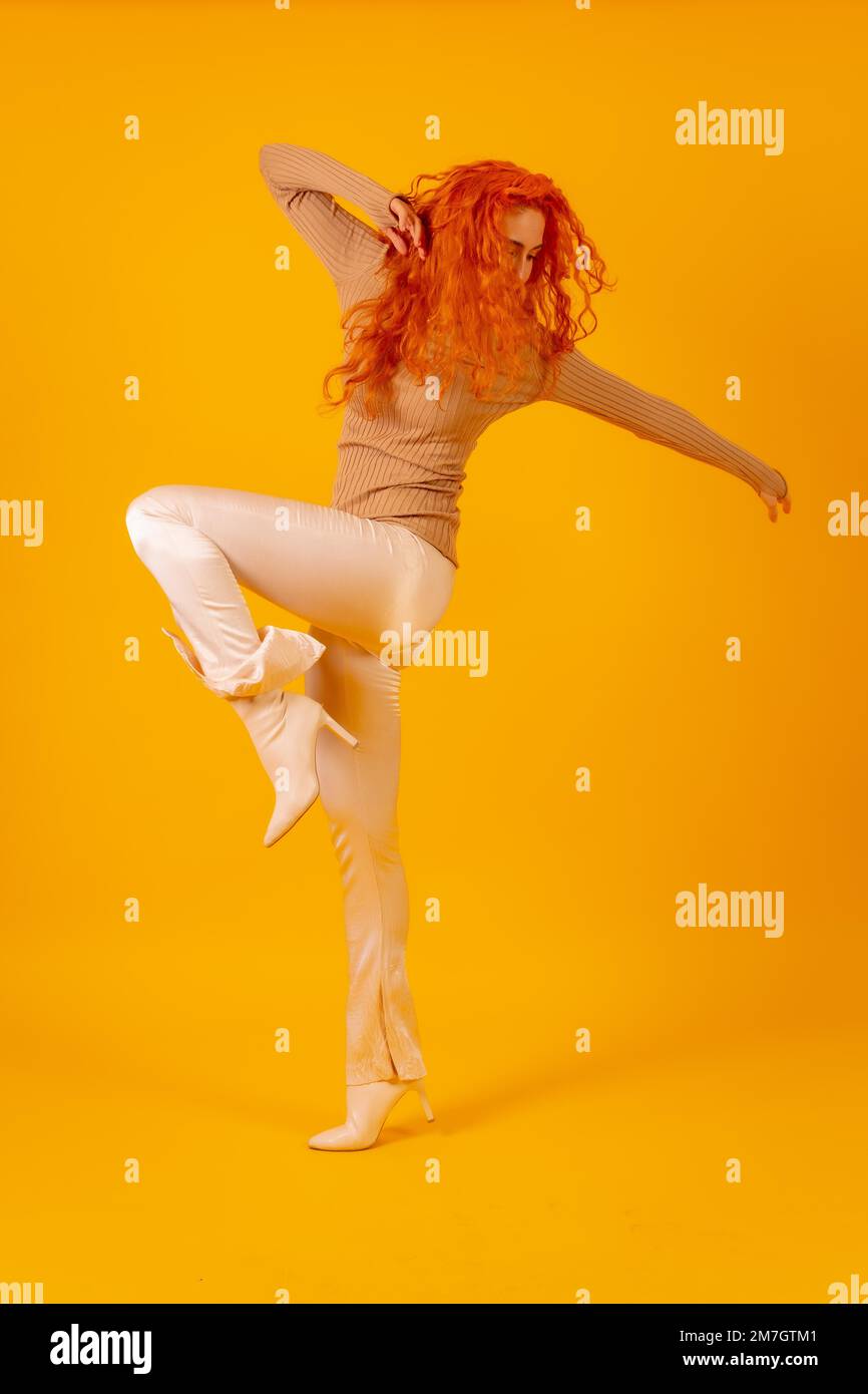 Red-haired woman on a yellow background, studio shot, fashion posed ...