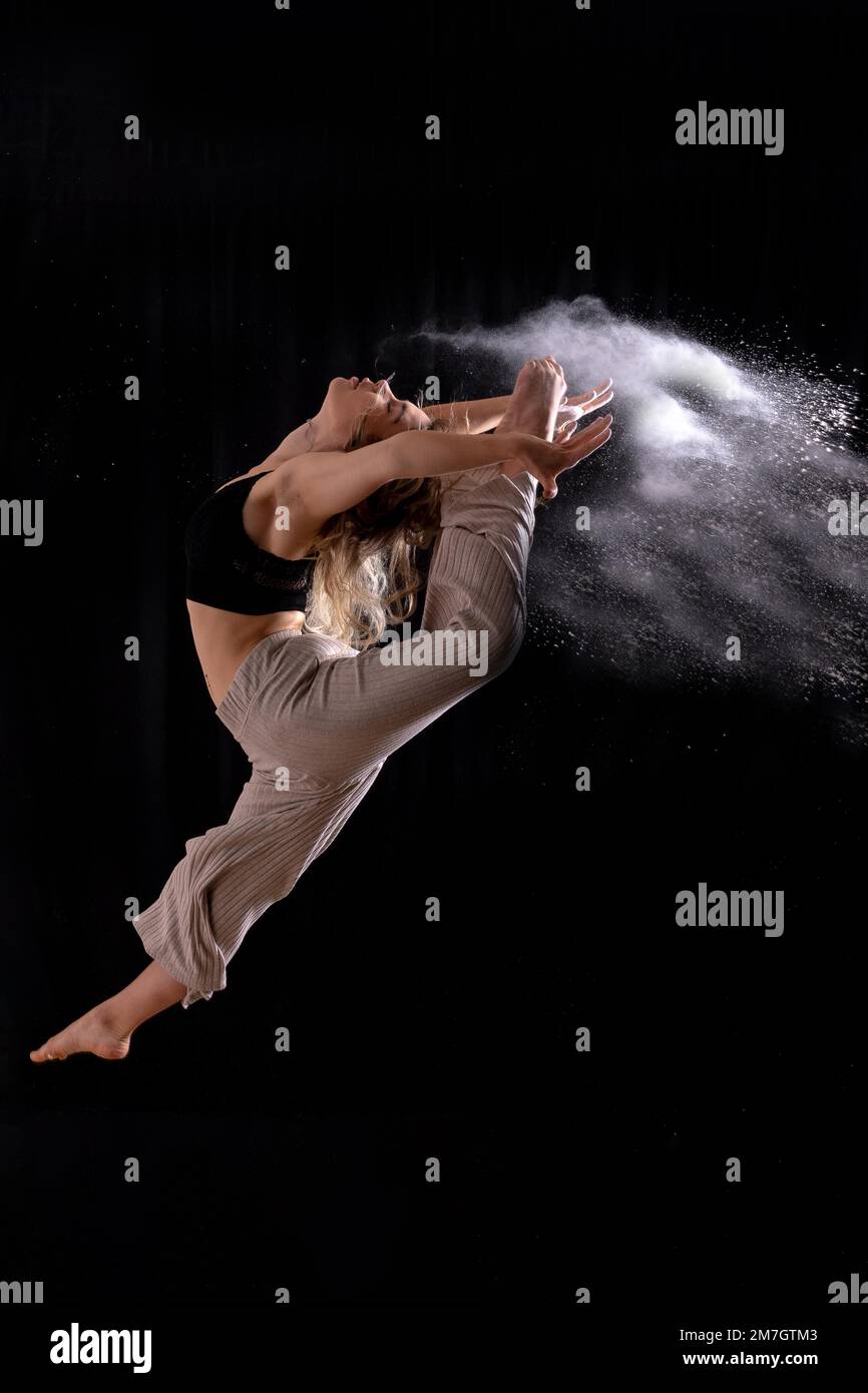 Young dancer performing a jump in studio photo session with a black ...
