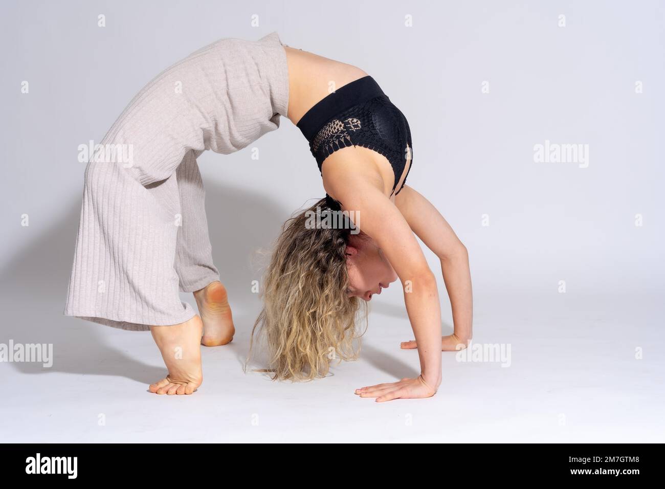 Young dancer in studio photo session with a white background, ballet, doing a bridge handstand ...