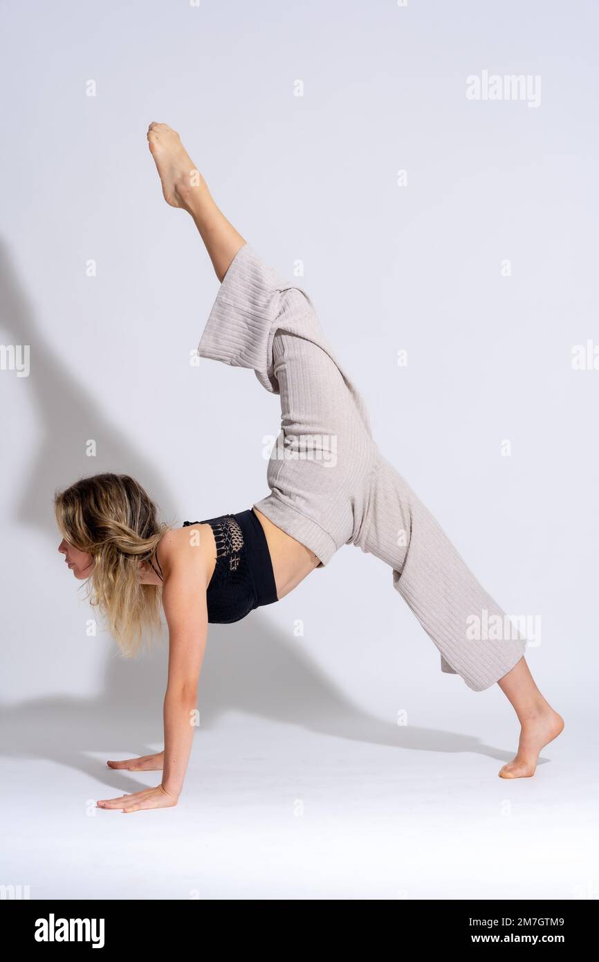 Young dancer in the studio raising her leg on a white background ...