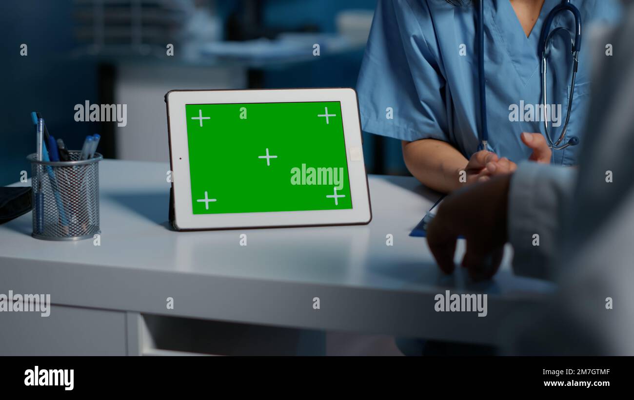 Nurse showing tablet computer with green screen display to doctor while ...