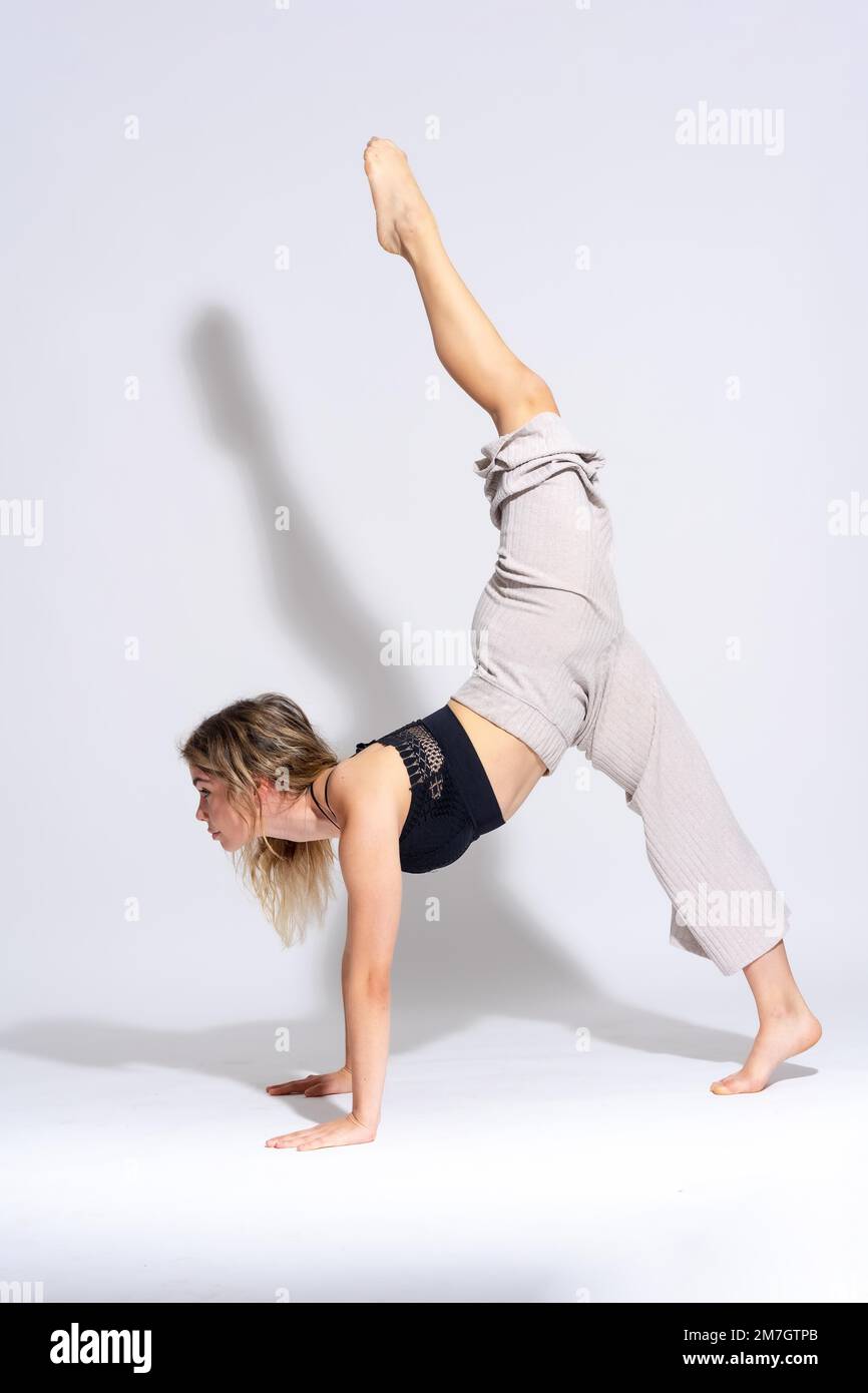 Portrait of young dancer in the studio raising her leg on a white ...