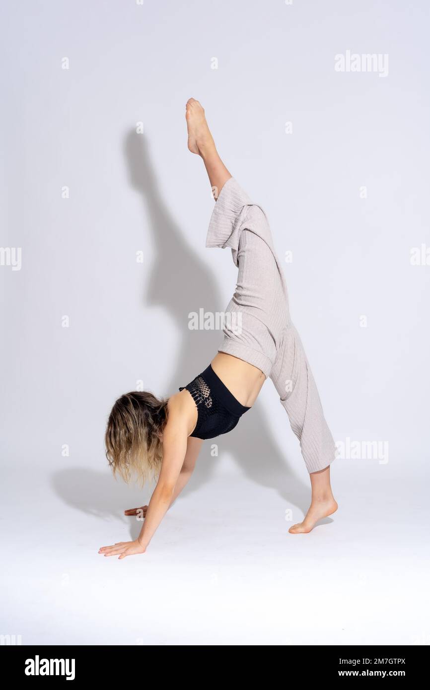 Young dancer in the studio raising her leg on a white background ...