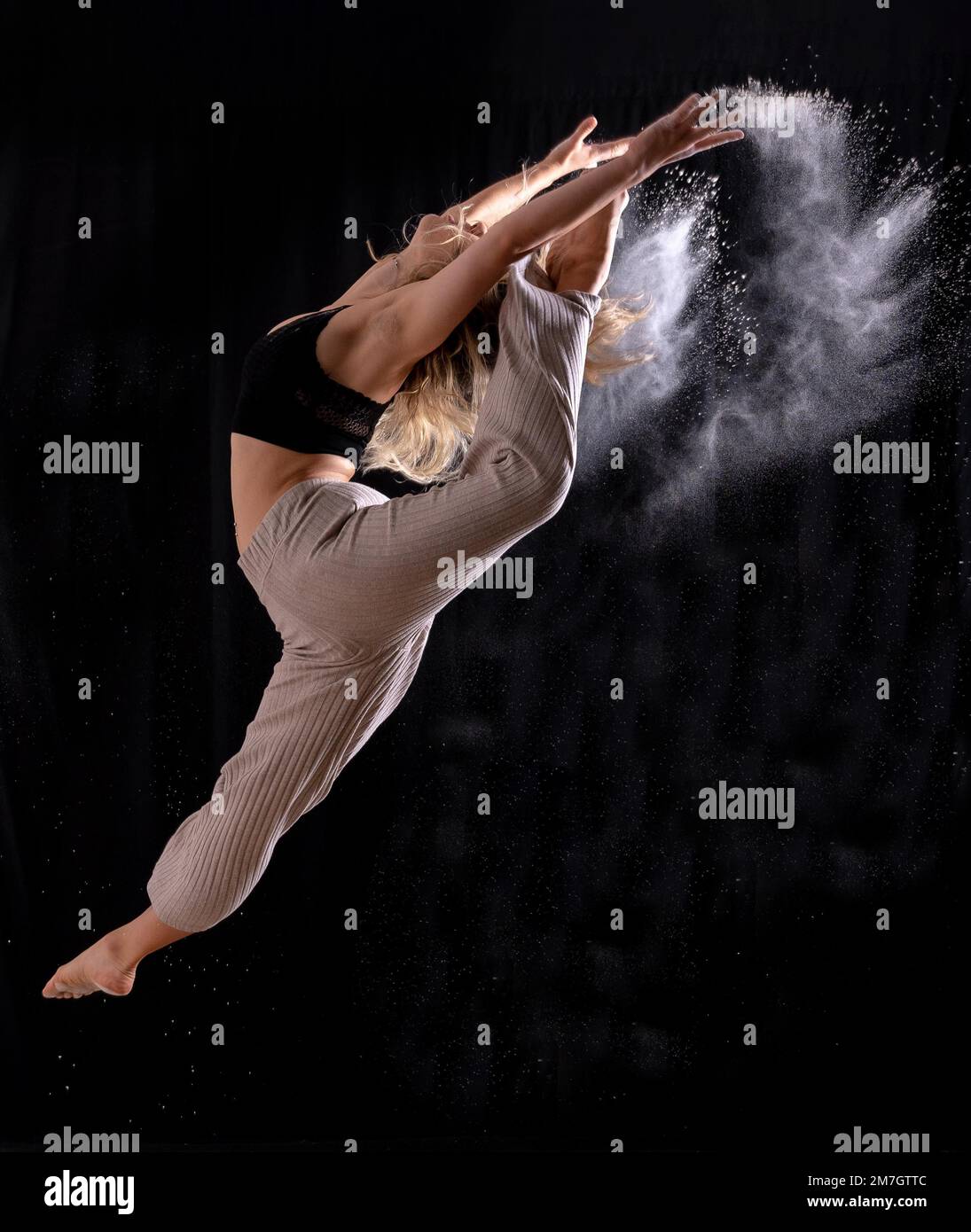 Young dancer performing a jump on a black background, ballet, freezing ...