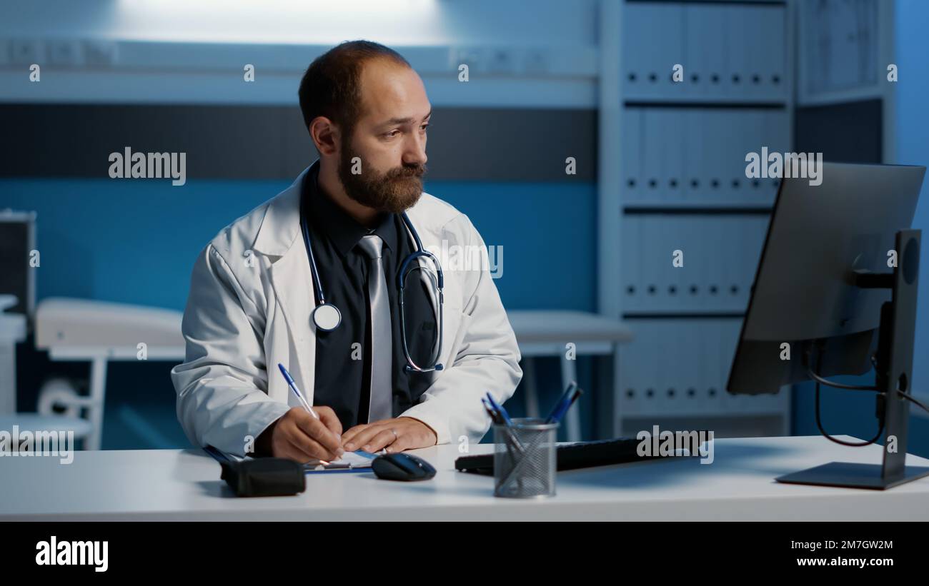 Tired stressed physician man working late at night in hospital office ...