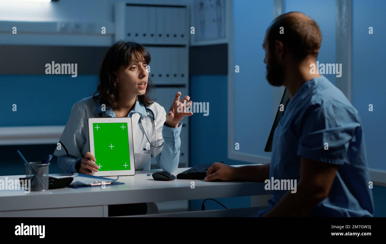 Medic holding tablet computer pointing at green screen chroma key ...