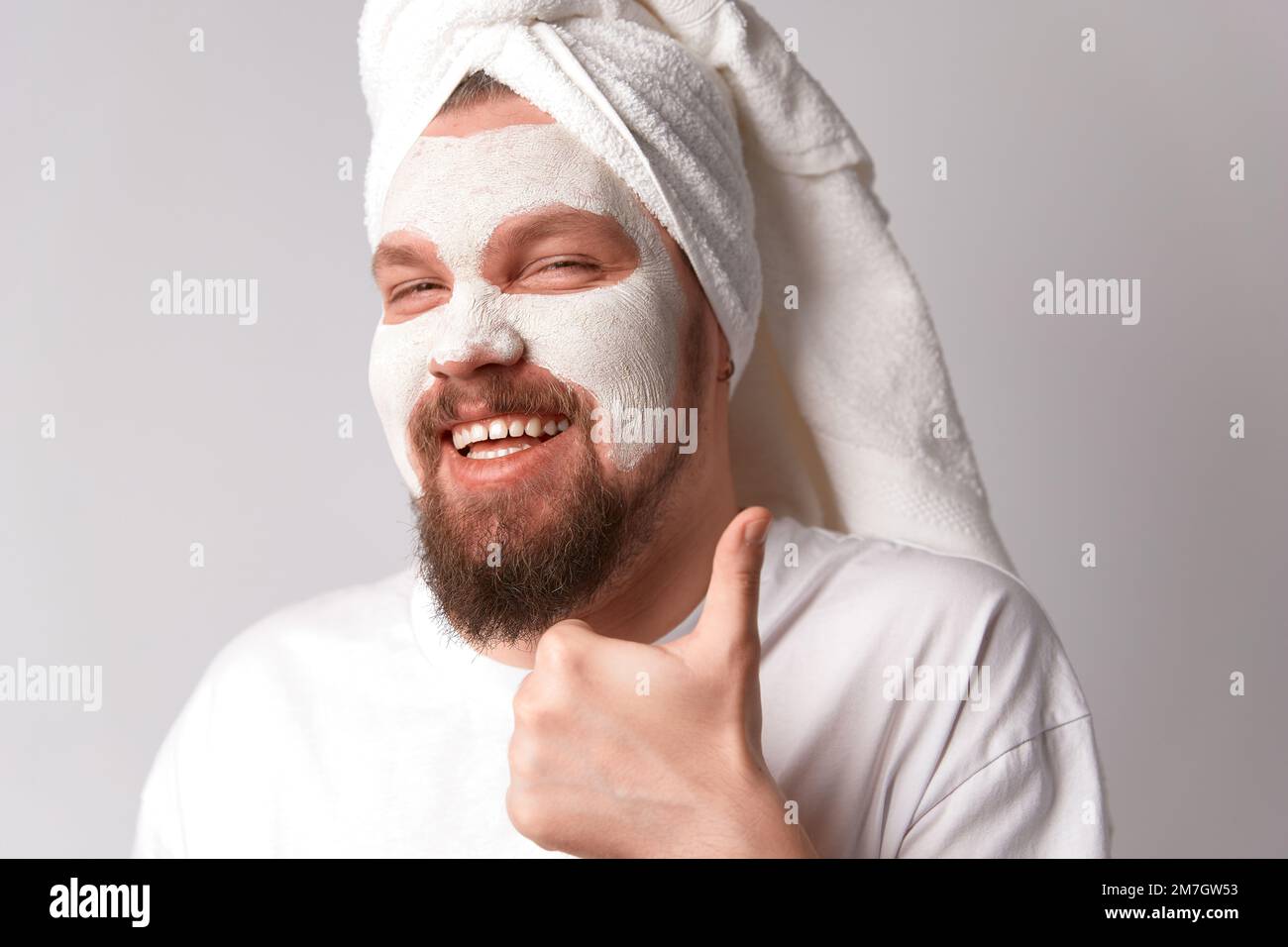 Man in white tshirt apply facial mask stand against white background ...