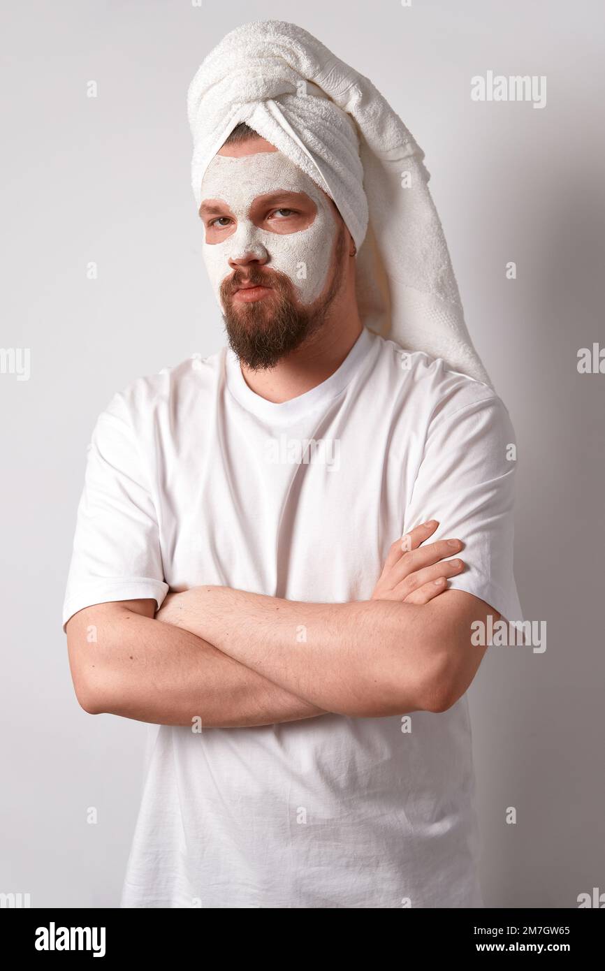 Man in white tshirt apply facial mask stand against white background ...